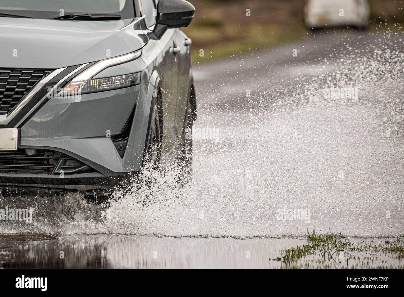 Water spray from a car wheel and the front section of the car as it ...