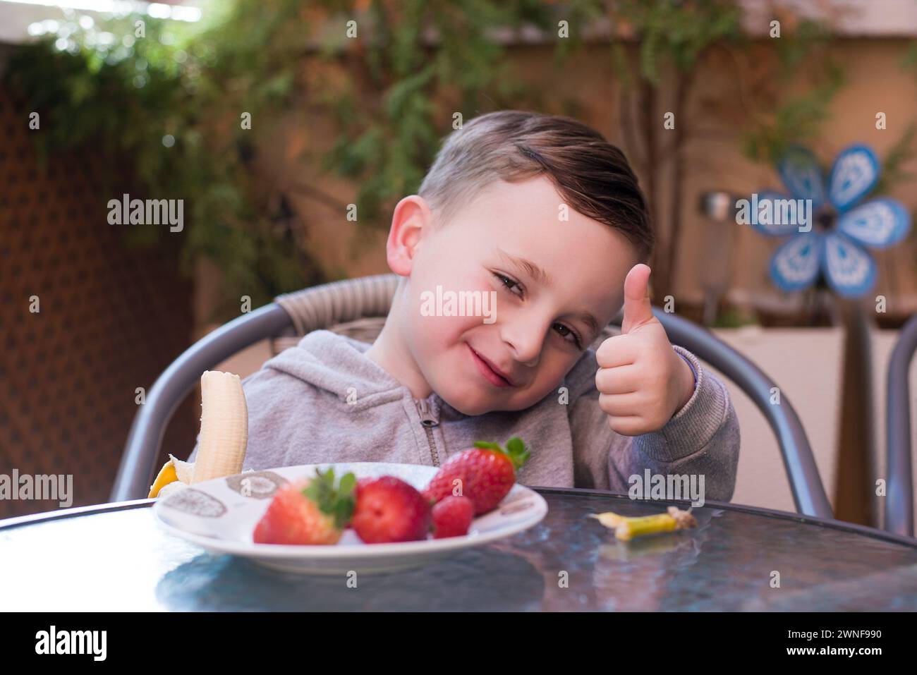 Cute baby 1,4 years old sitting on high children chair and eating fruit ...