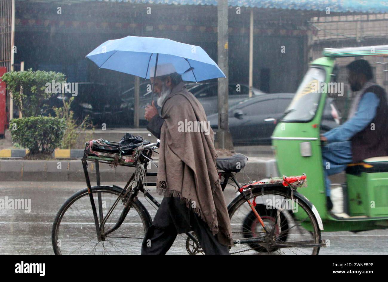 PESHAWAR, PAKISTAN, MAR 02: Commuter holds umbrella over his head to ...