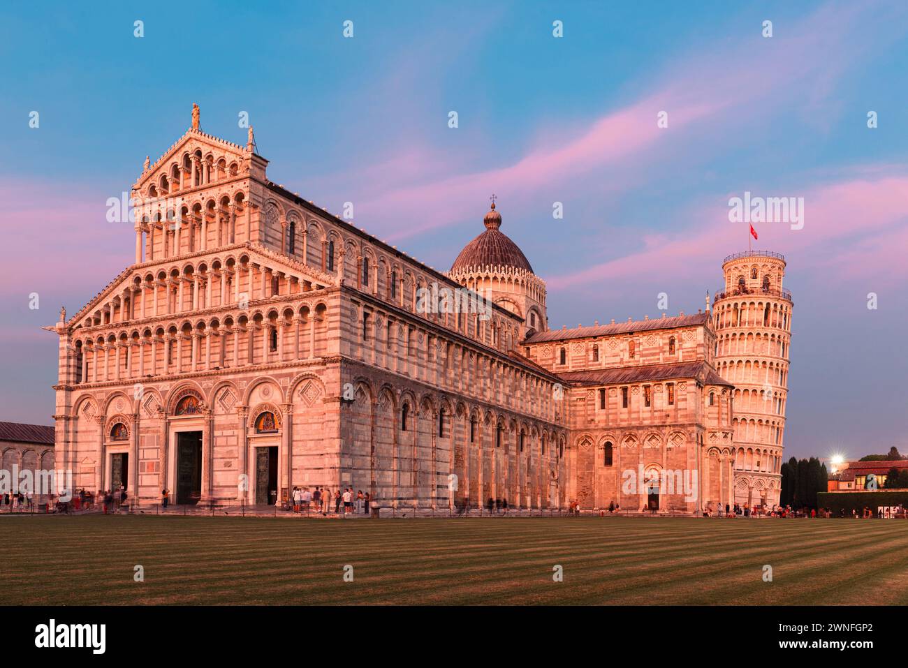 The Cathedral and the Leaning Tower of Pisa glow in the pink light of ...