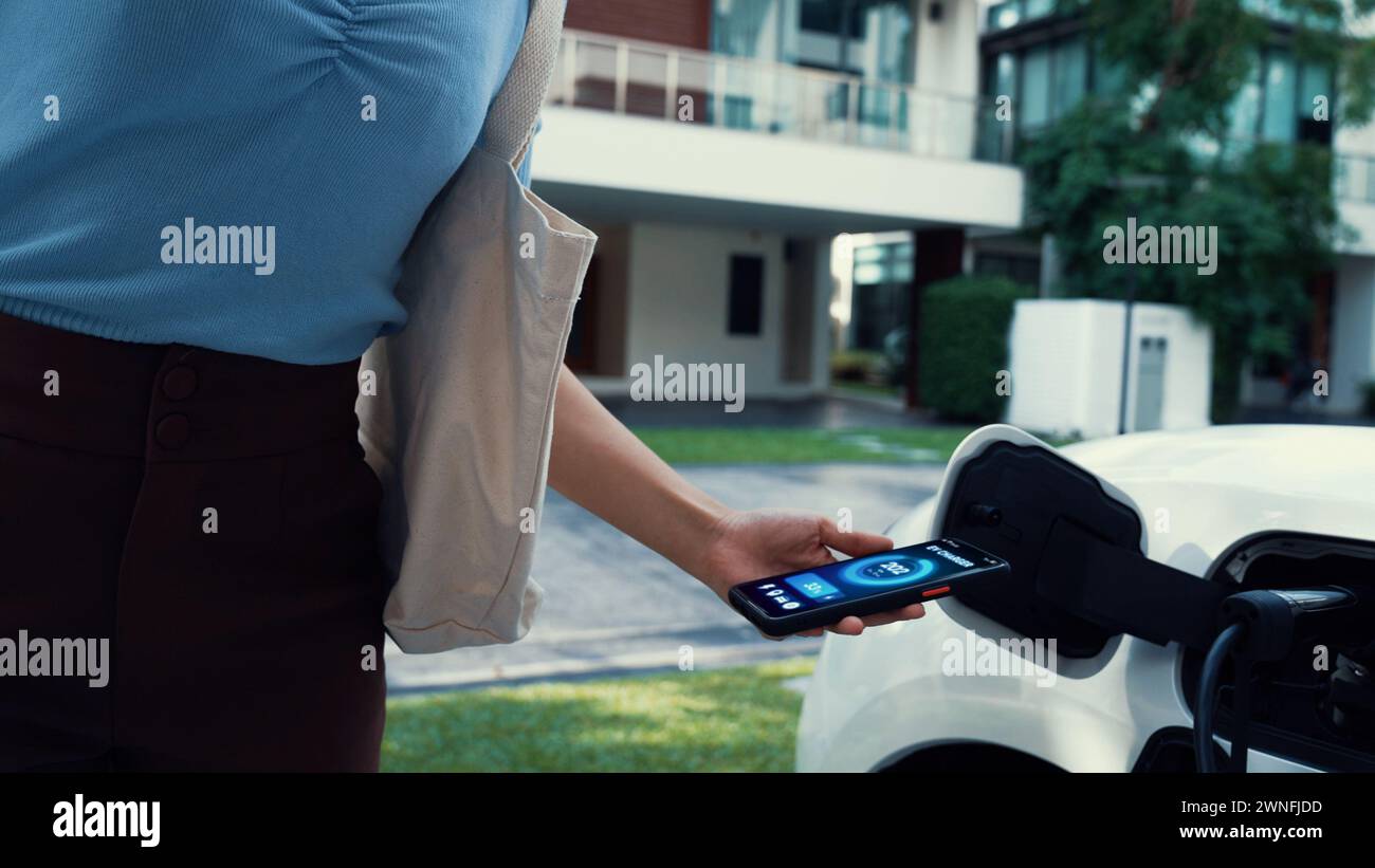 Modern woman recharge her EV car from home charging station by EV ...