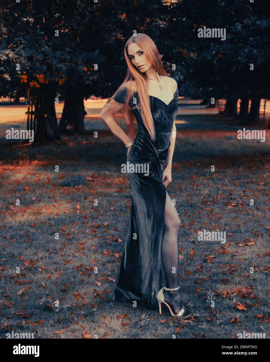 On fire, a model poses in a long dress with trees in the background ...