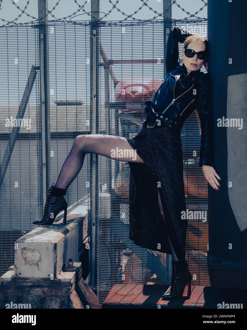 Fenced in, a fashion model poses against a fence Stock Photo - Alamy