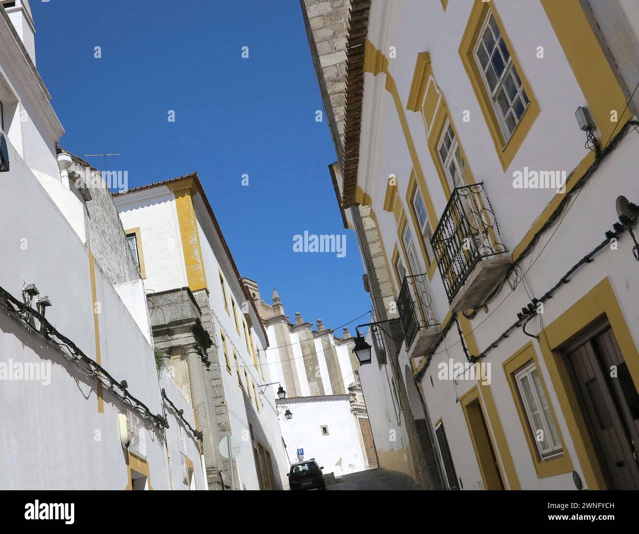 White facades and colorful windows. Old urban street in Evora town ...