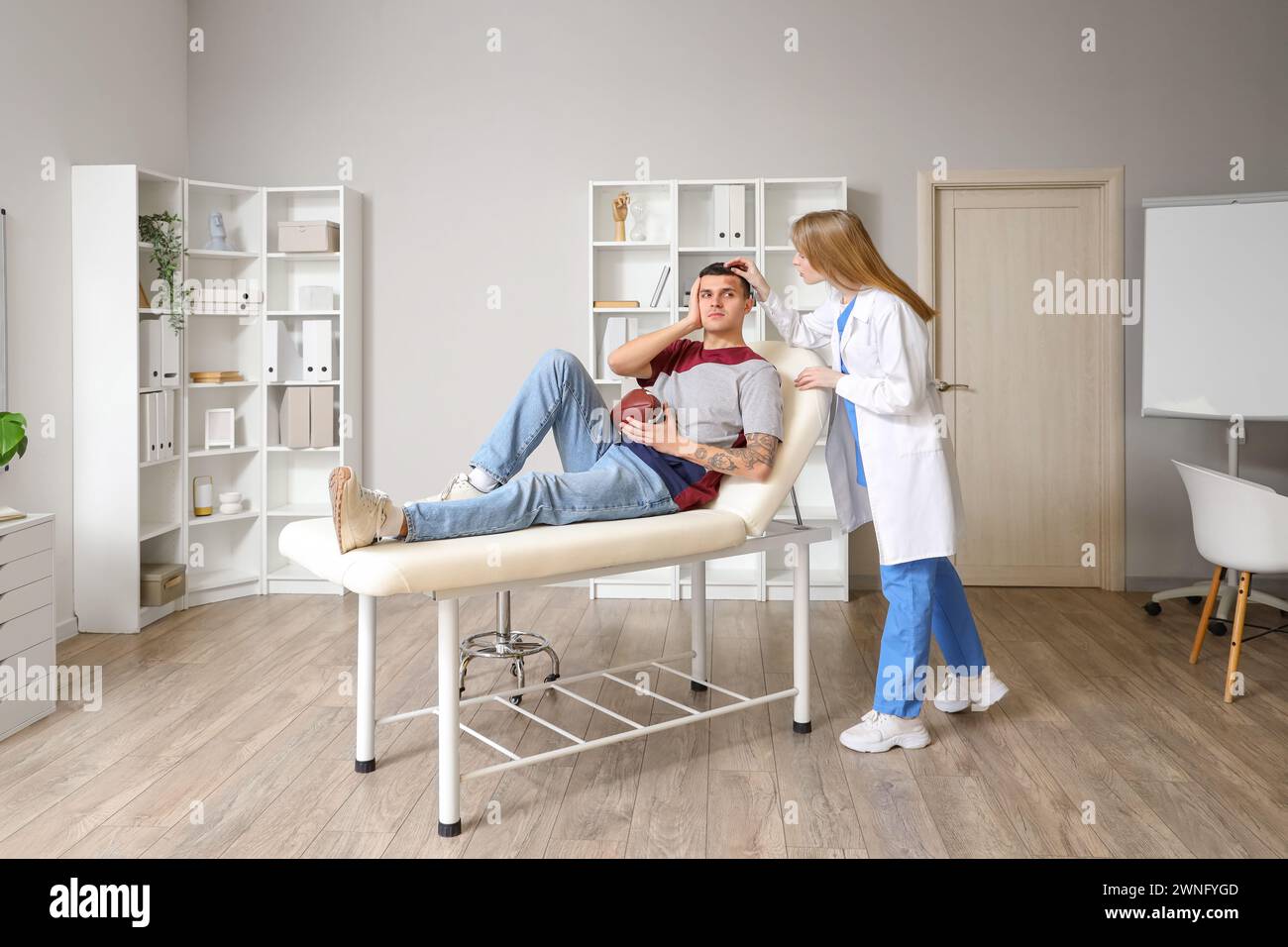 Female doctor examining rugby player with brain concussion in clinic ...
