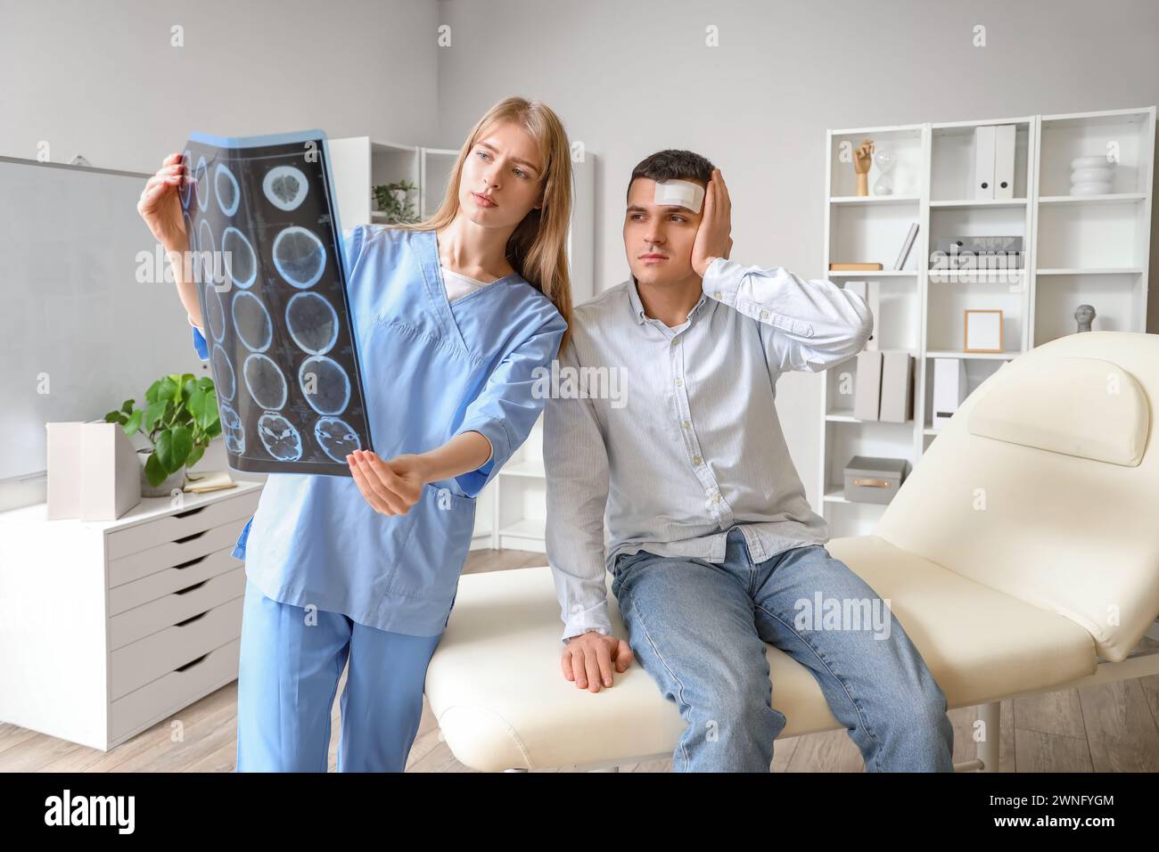 Female doctor and man with brain concussion examining MRI scan in ...