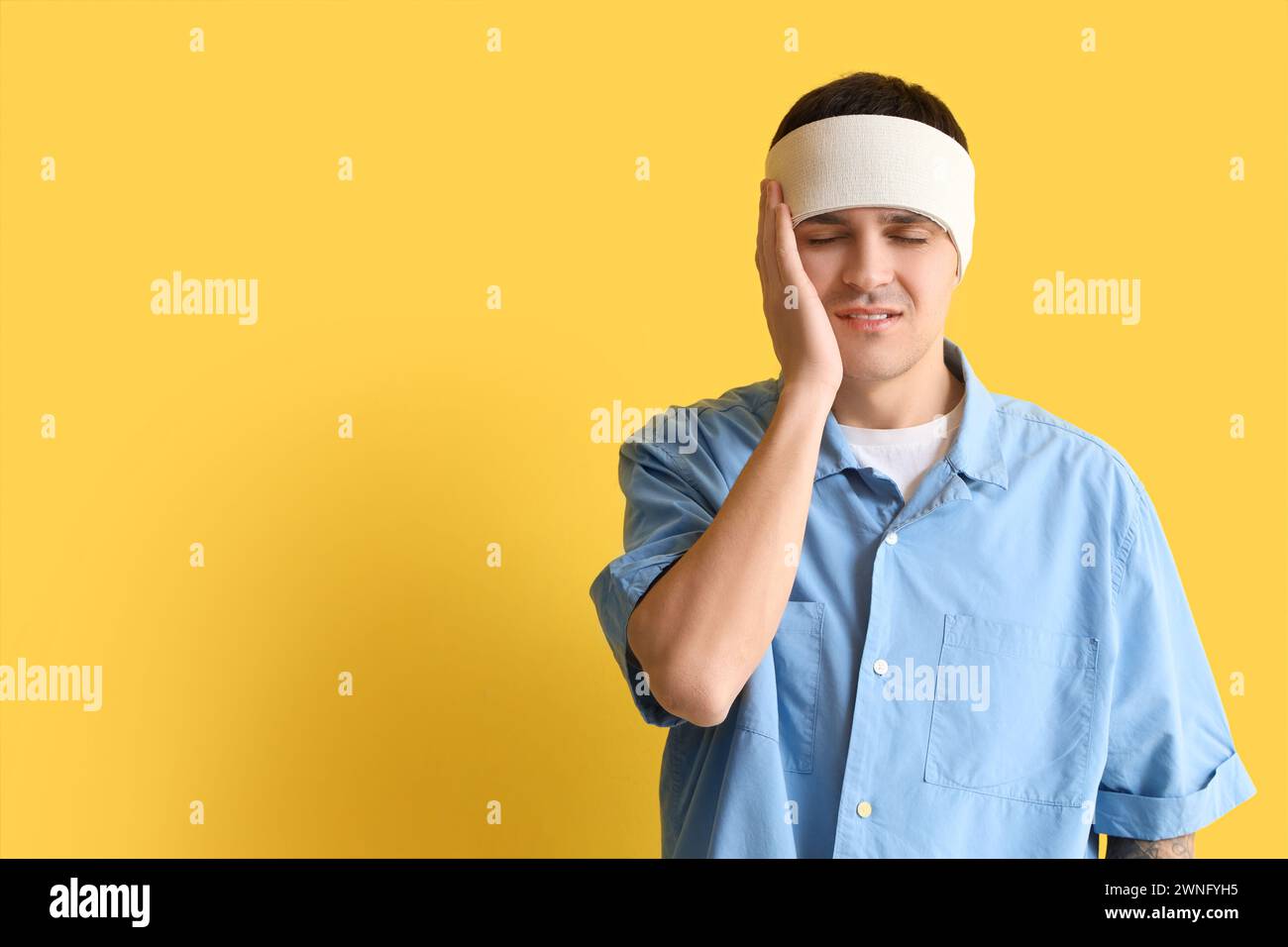 Young man with brain concussion and bandaged head on yellow background ...