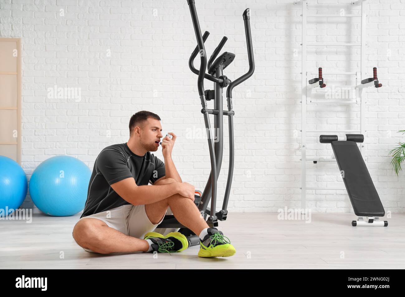 Sporty young man using inhaler in gym Stock Photo - Alamy