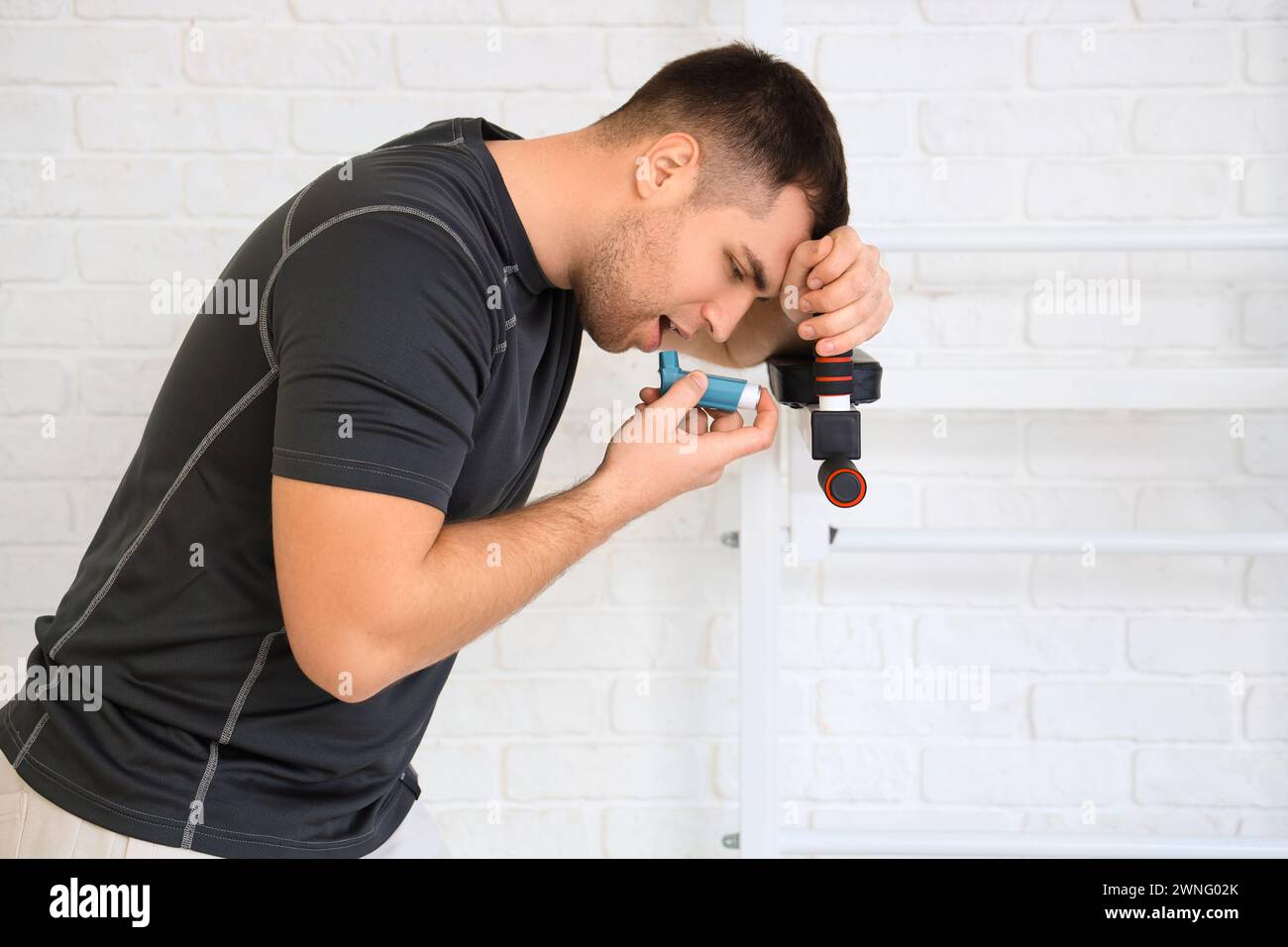 Sporty young man using inhaler in gym Stock Photo - Alamy