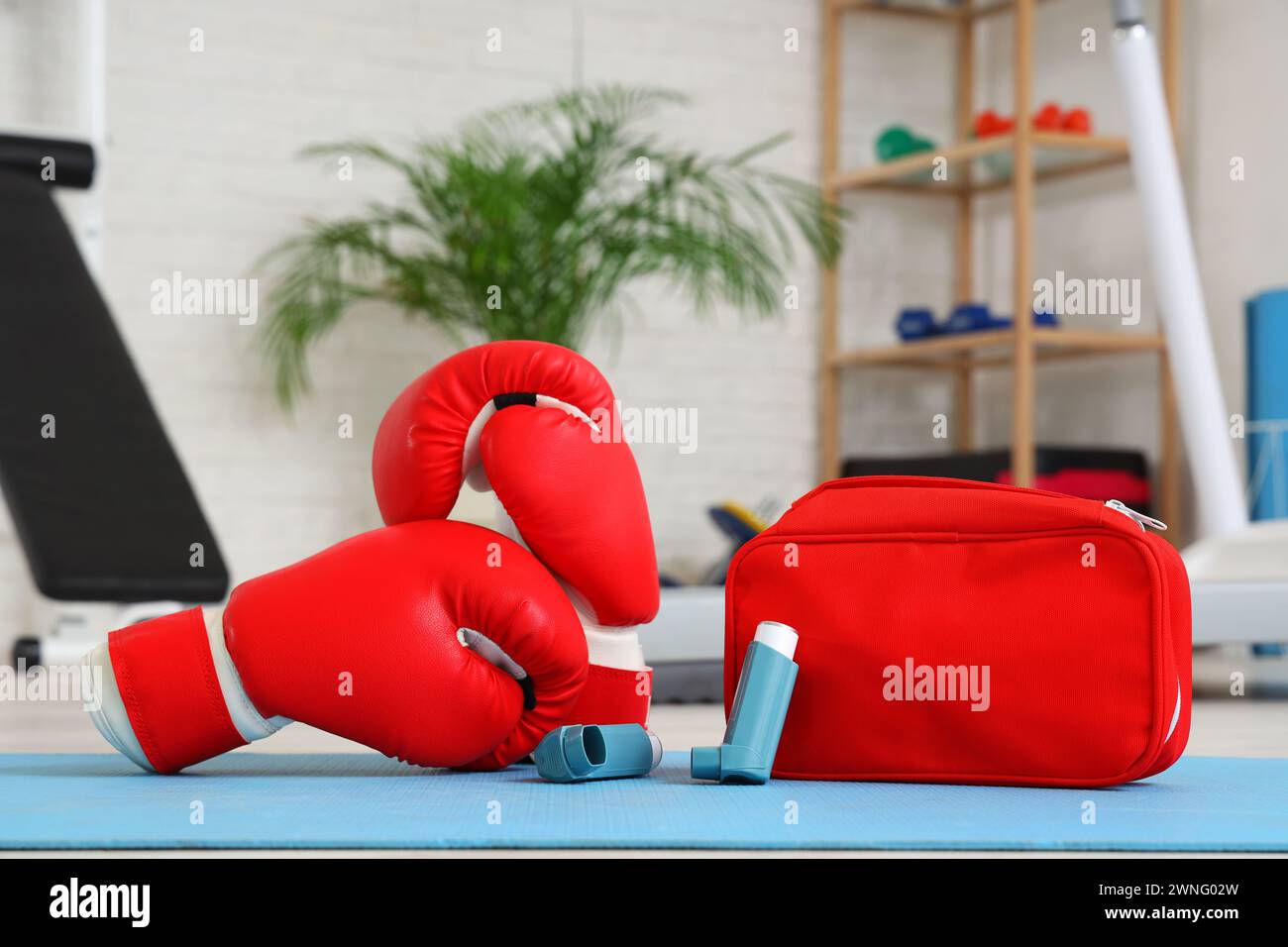 Asthma inhalers with boxing gloves and first aid kit on mat in gym ...