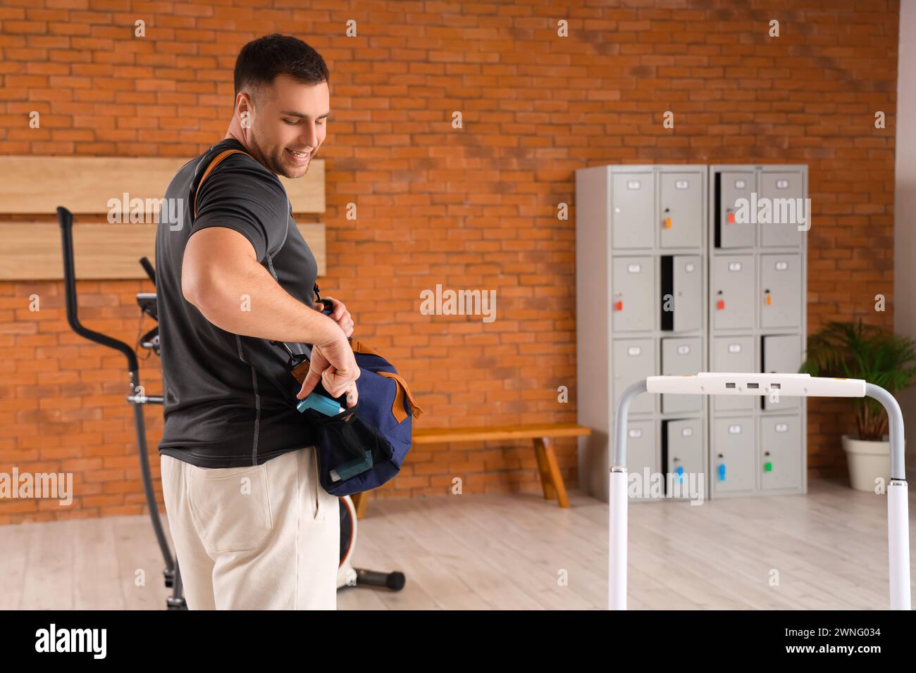 Sporty young man putting inhaler into bag in gym Stock Photo - Alamy