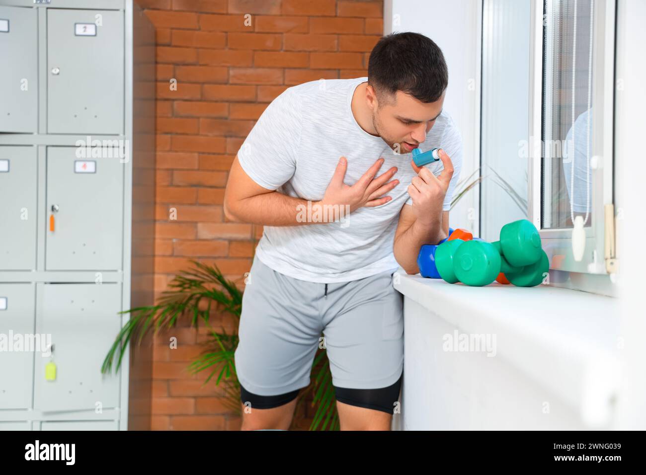 Sporty young man with asthma attack using inhaler in gym Stock Photo ...