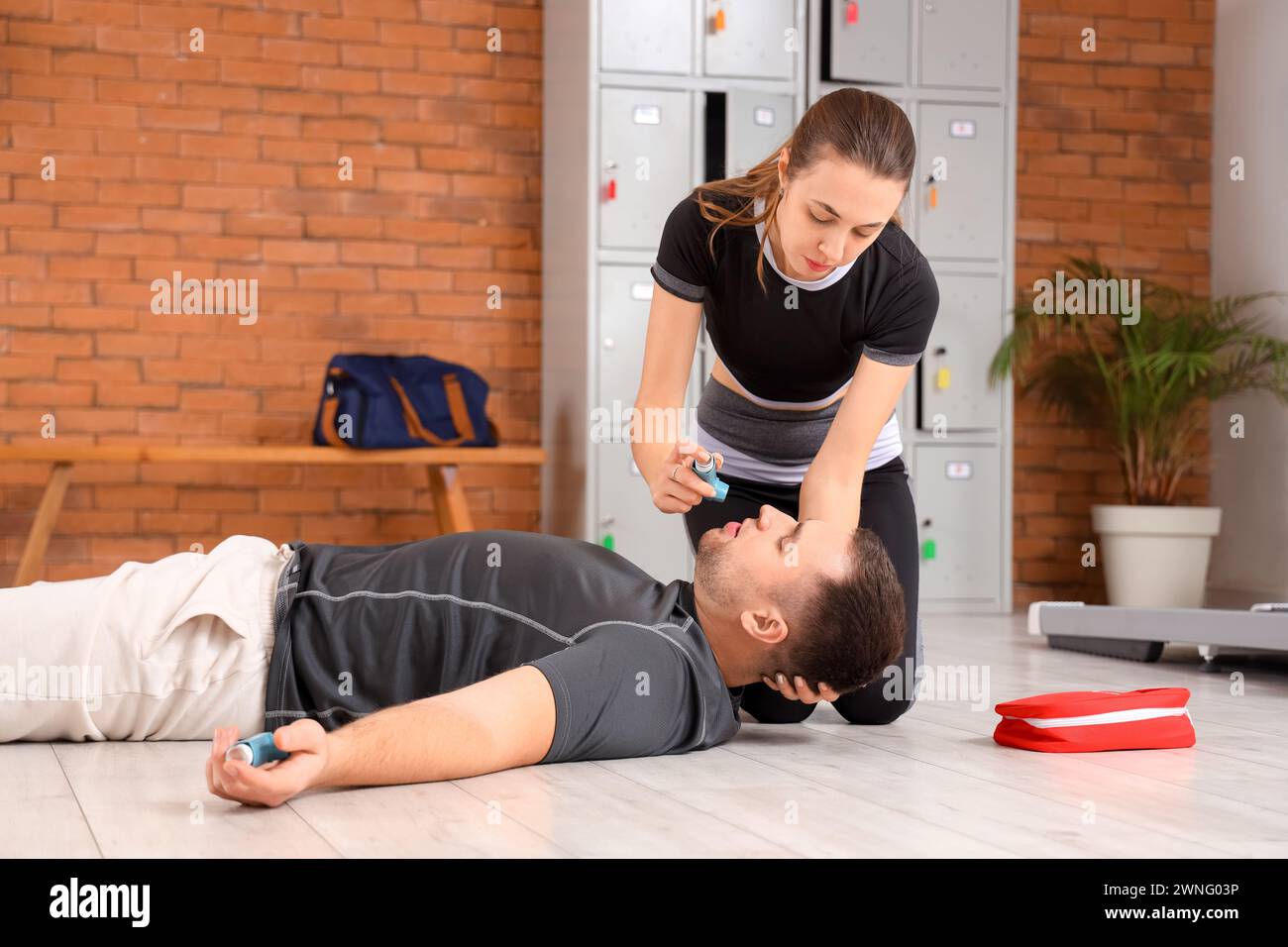 Female trainer with inhaler giving man first aid in gym Stock Photo - Alamy