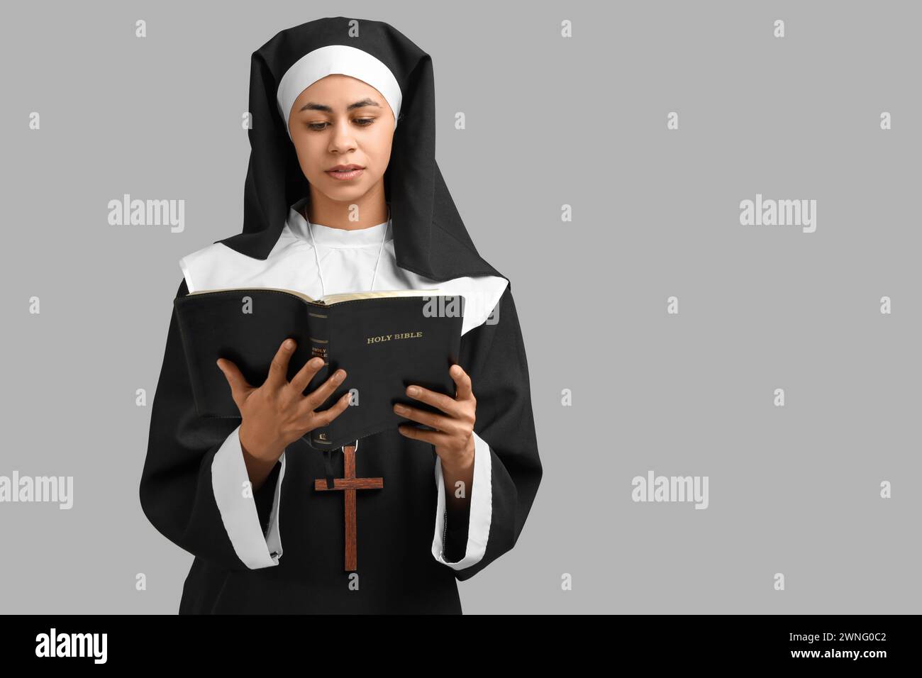 Portrait of young nun reading Bible on grey background Stock Photo - Alamy