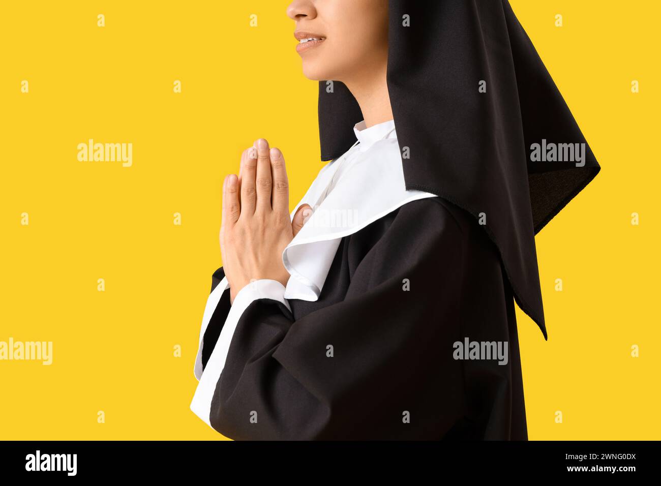 Young nun praying on yellow background Stock Photo - Alamy