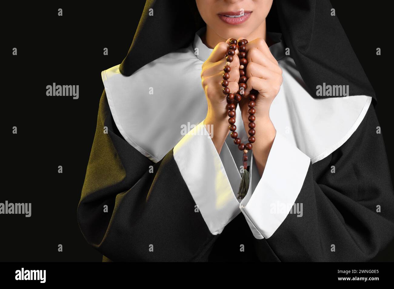 Praying young nun on black background, closeup Stock Photo - Alamy