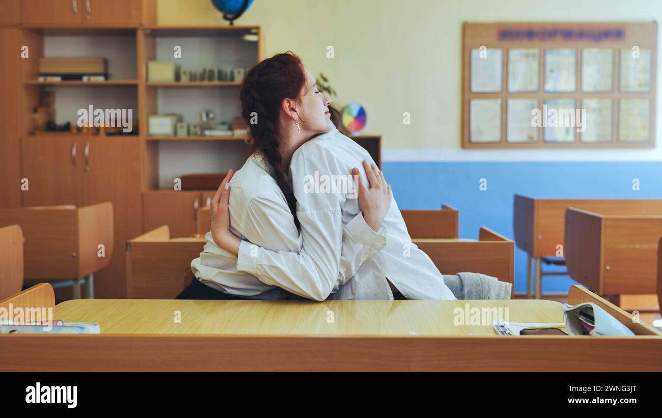 Girl students hugging in a classroom at school Stock Photo - Alamy