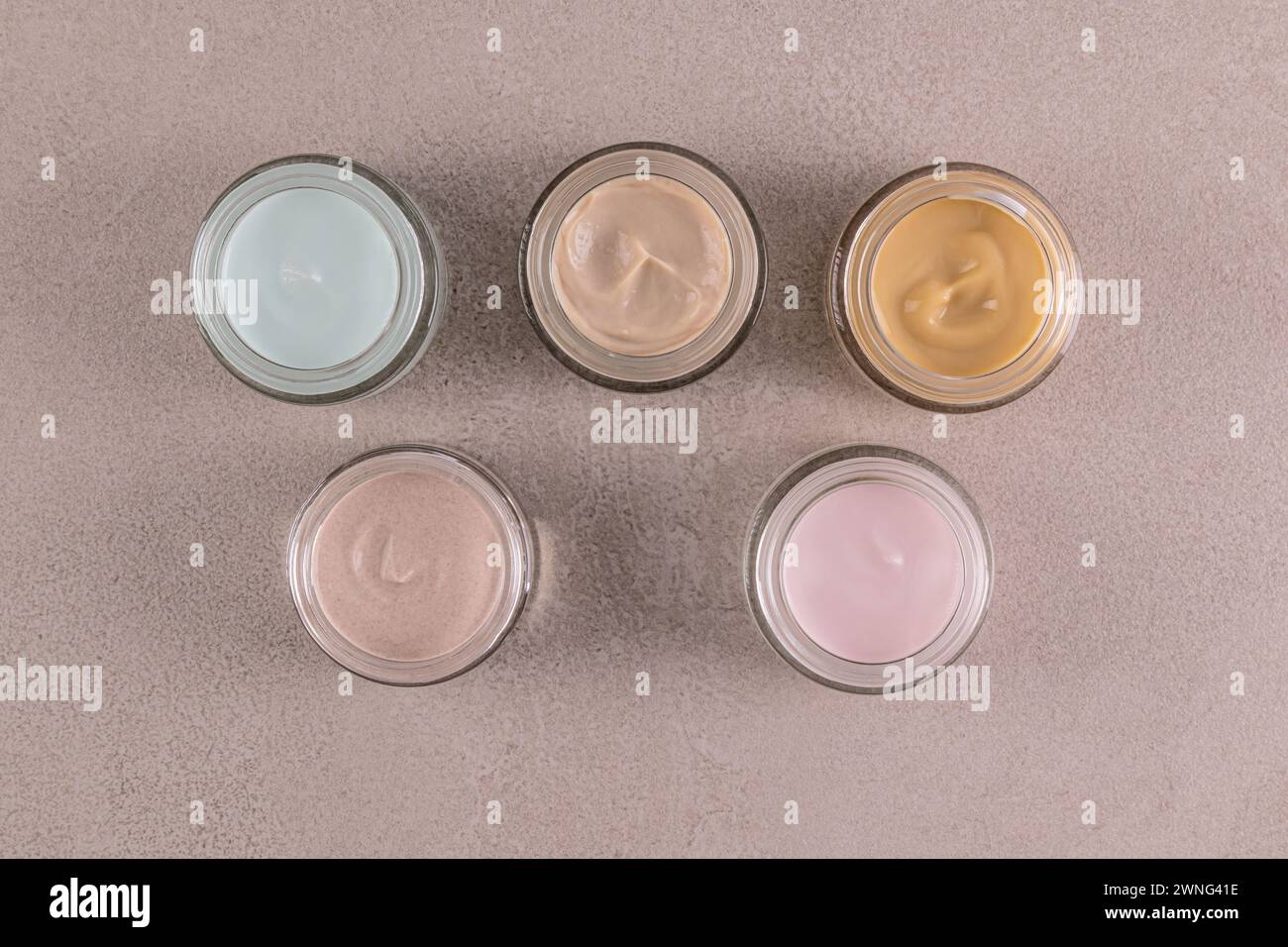 A set of glass jars with cosmetic cream of different colors for face ...