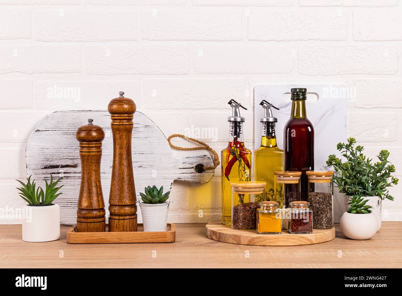 Lots of different kitchen utensils, oil bottles, spice mill and potted ...