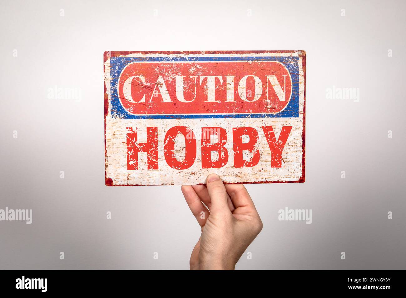 HOBBY. Metal warning sign in a woman's hand on a white background Stock ...