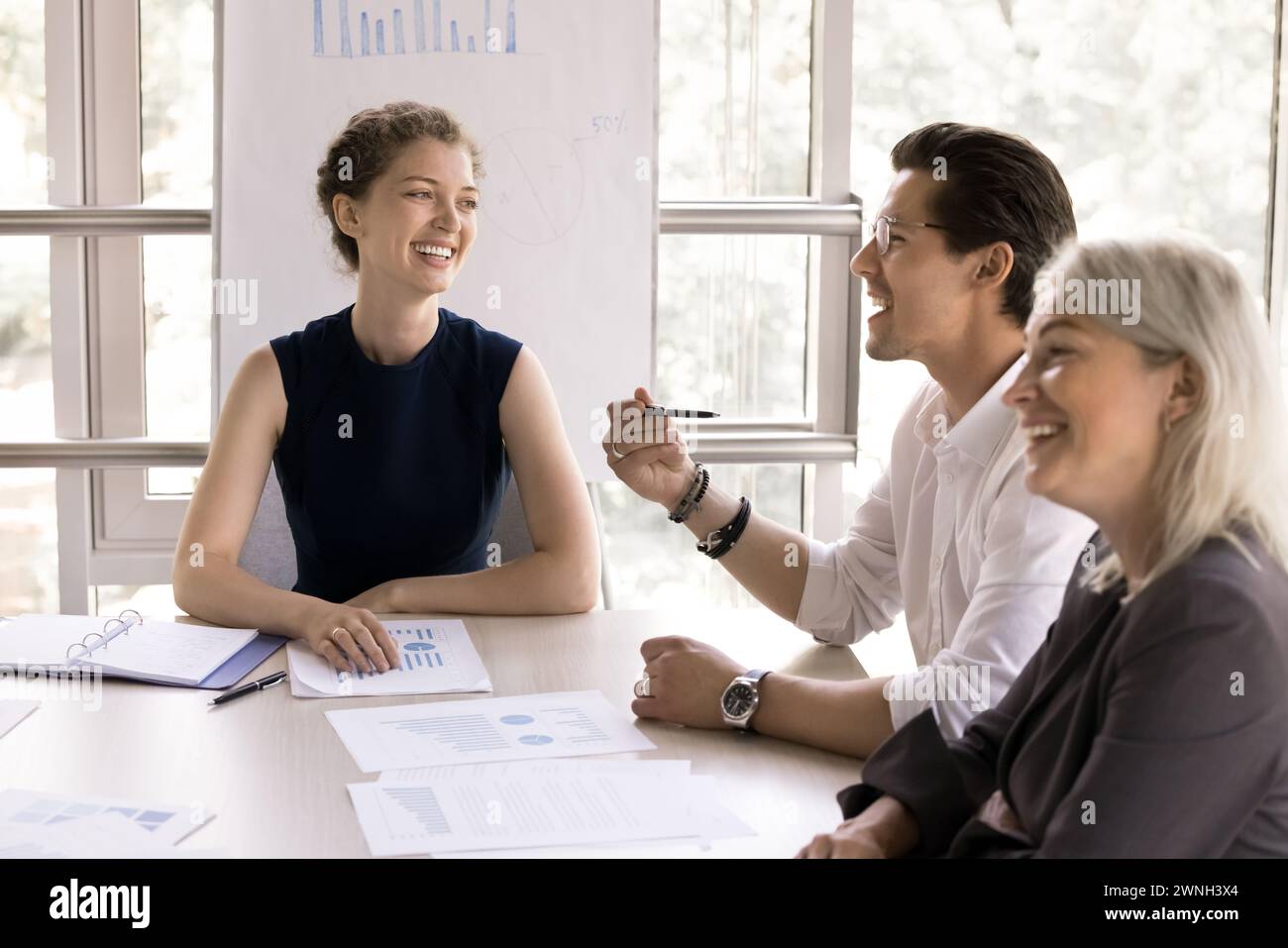 Three happy businesspeople talking gathered in conference room Stock ...