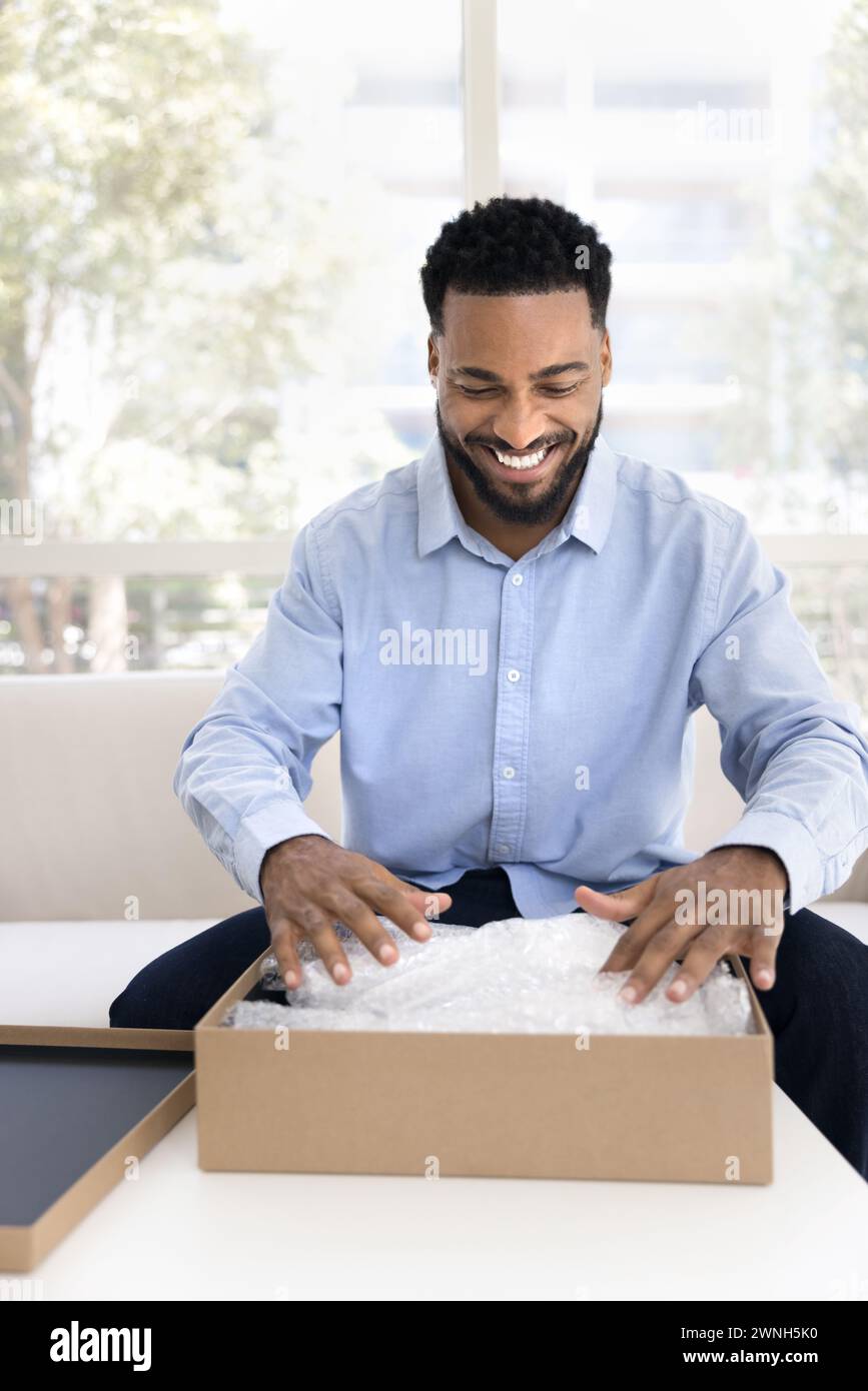 Joyful Black client man getting parcel from transportation logistic ...