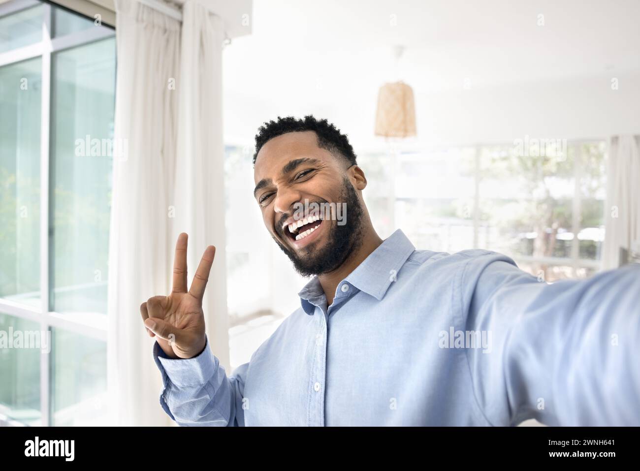 Happy joyful African American guy showing victory winner fingers sign ...