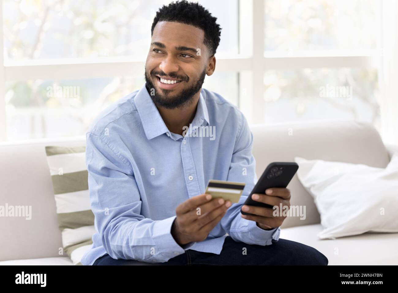 Happy young Black customer man paying by credit card Stock Photo - Alamy