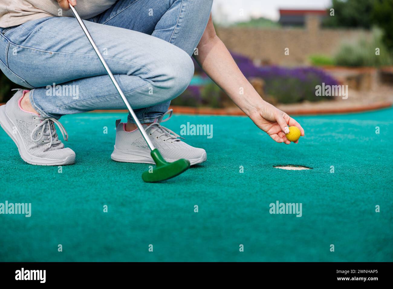 Woman plays mini golf and taking ball out from the hole after ...