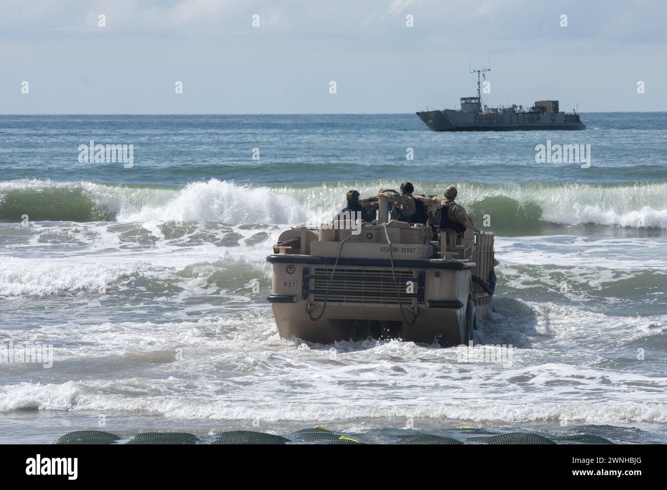 U.S. Navy Sailors, assigned to Beachmaster Unit 1, on the shore with a ...
