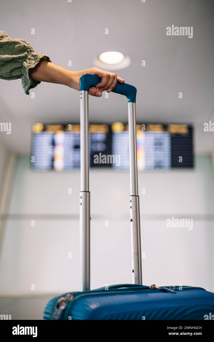 traveler's hand holding the handle of his luggage while waiting to ...