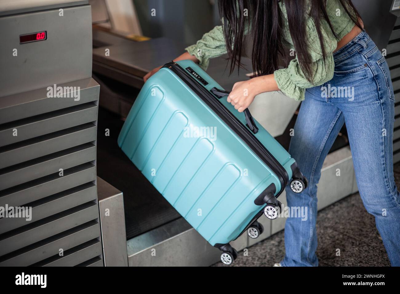 girl putting suitcase on the scale at the airport check-in counter to ...