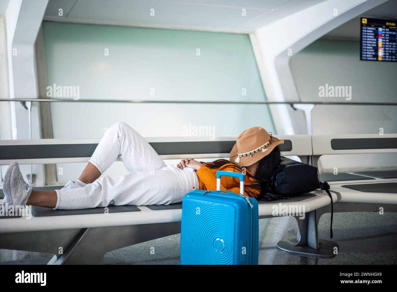 girl sleeping at the airport with hat over her face lying on the ...