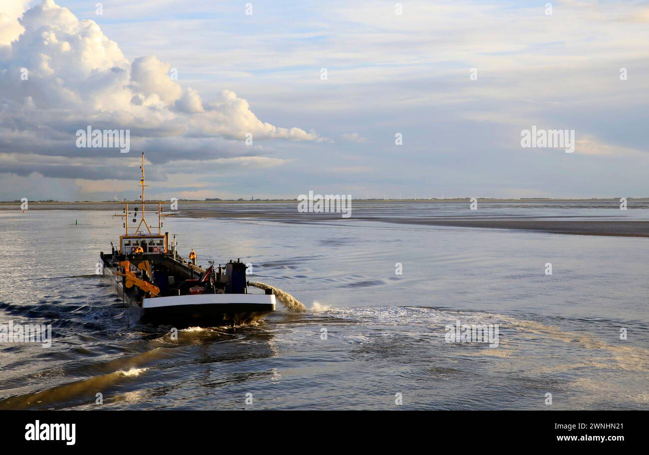 Dredger vessel in the Wadden Sea preventing the fairway from silting up ...