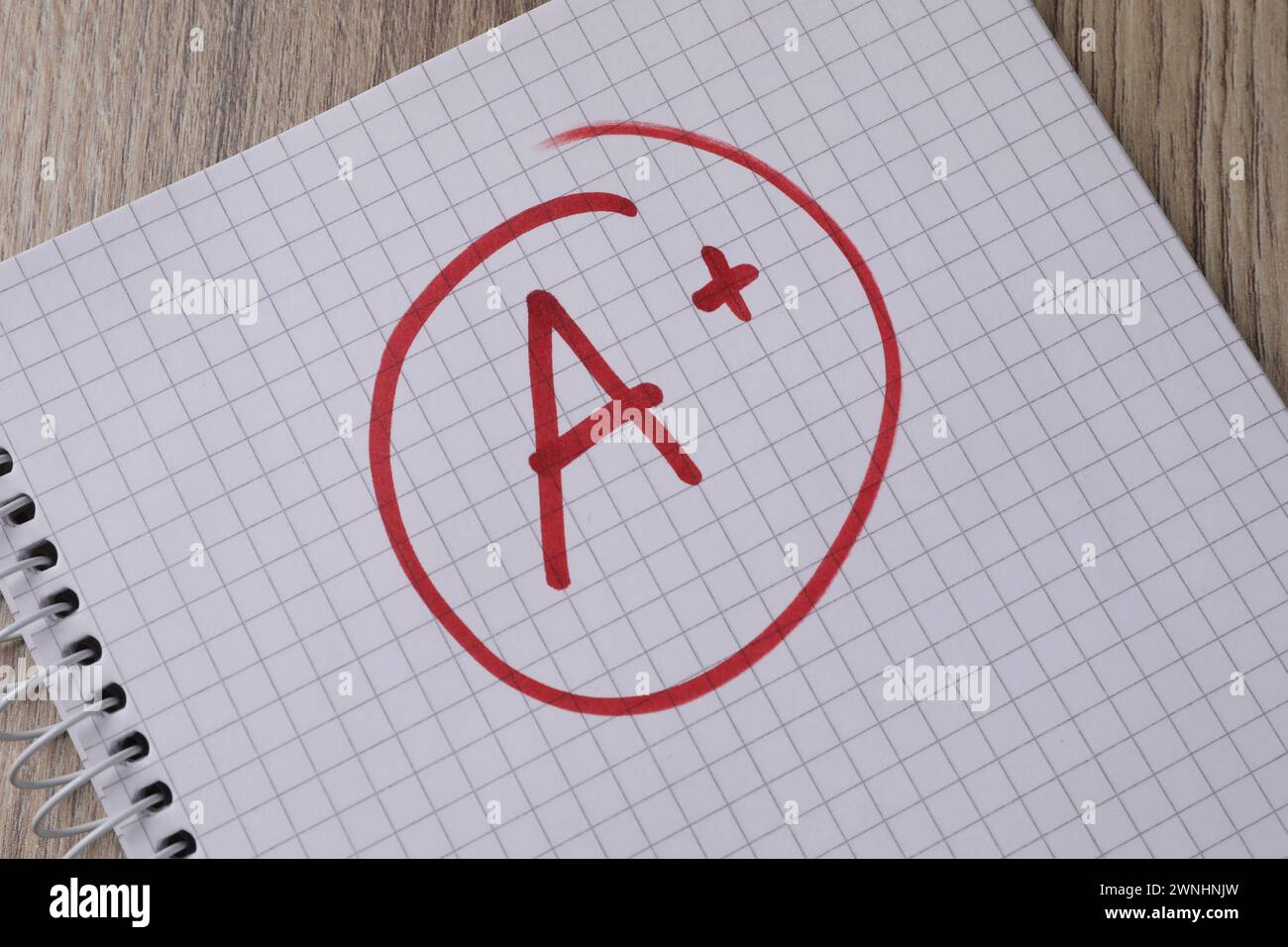 School grade. Red letter A with plus symbol on notebook paper on table ...