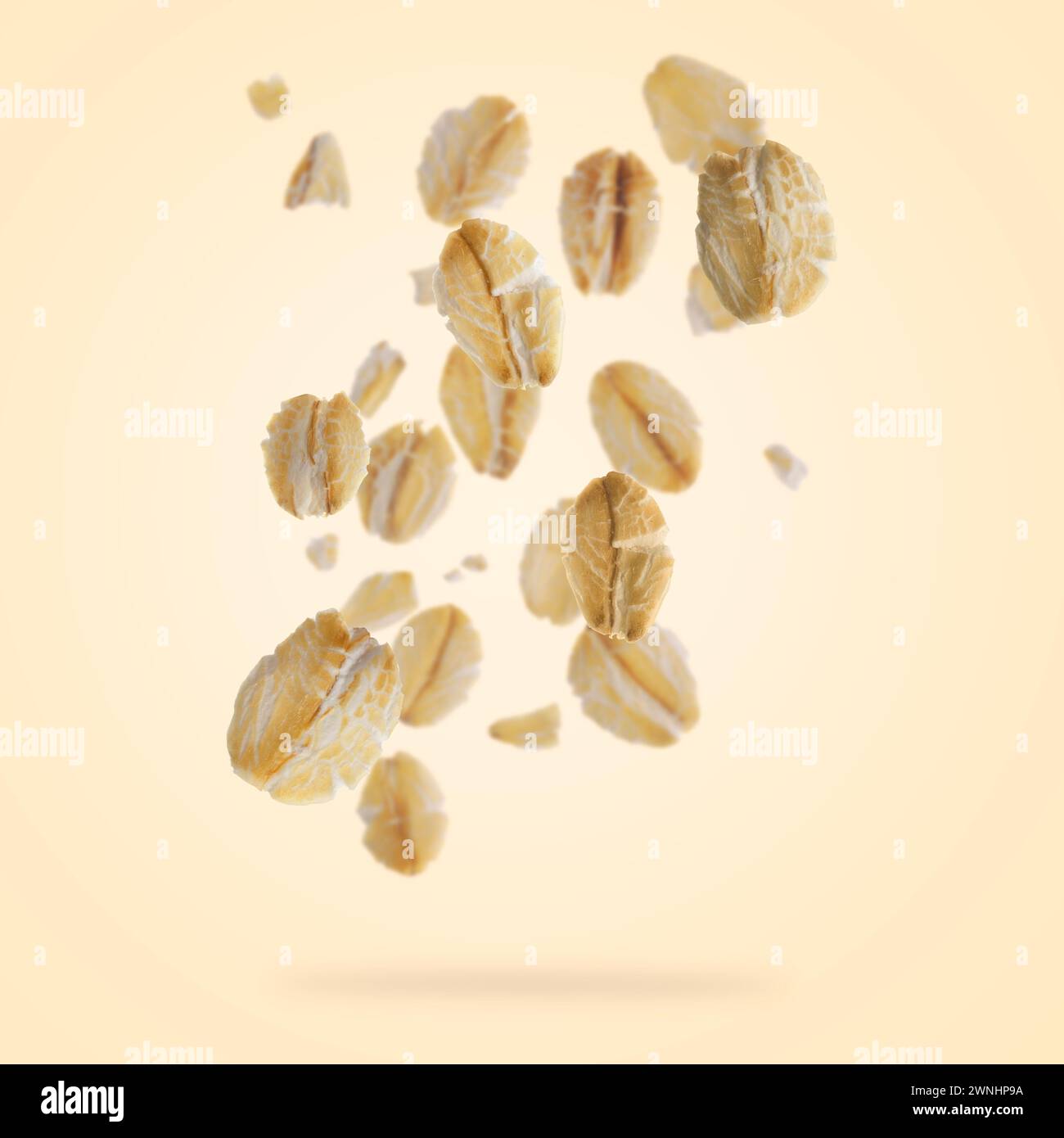 Rolled oat flakes falling on beige background Stock Photo - Alamy