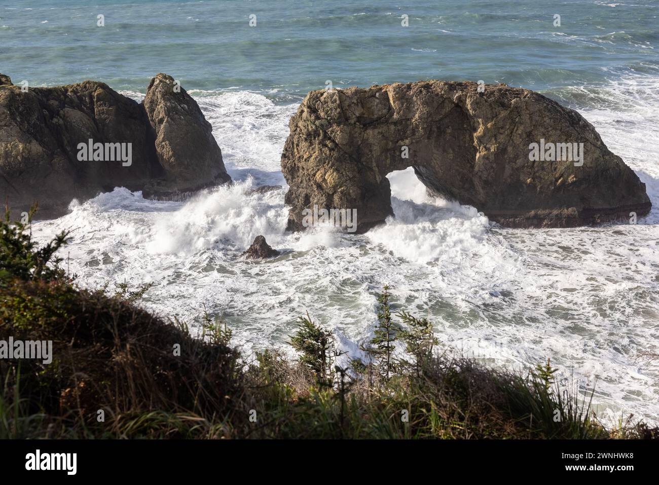 The ocean waves crash against the rocks, creating a powerful and ...