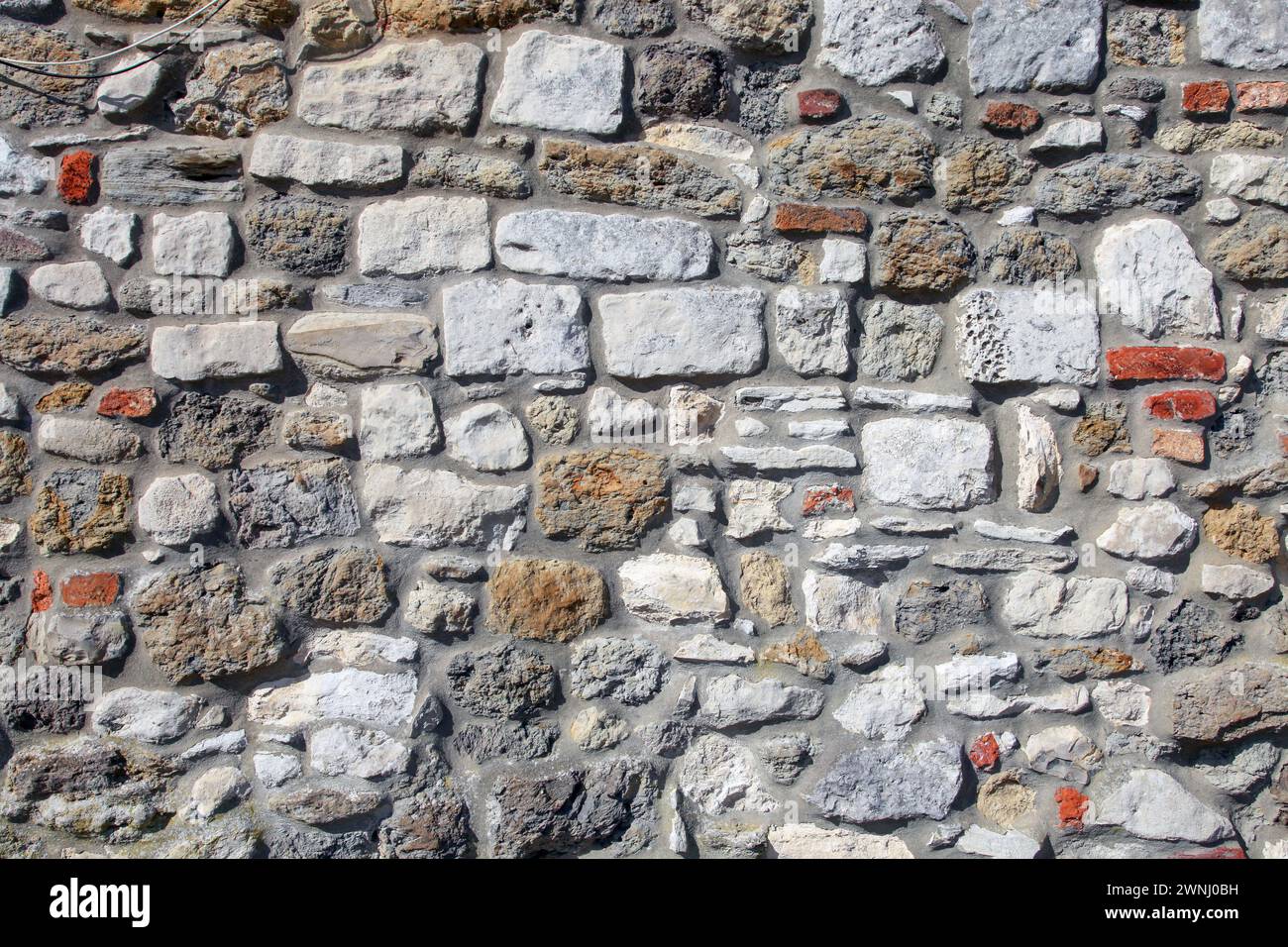 A wall made from assorted rocks including grey limestone and portland ...