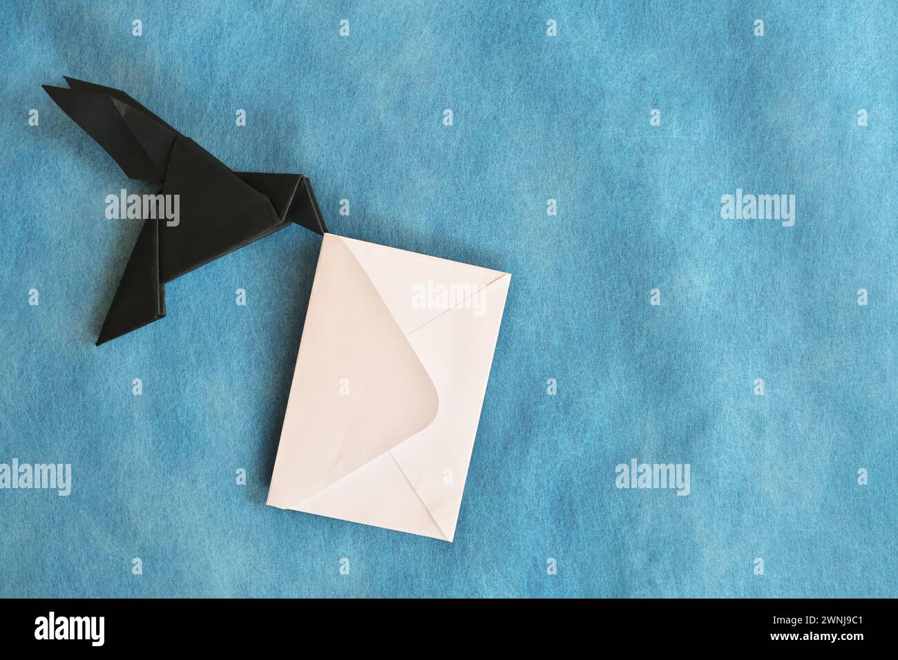 Black raven paper origami carrying white letter envelope. Email ...