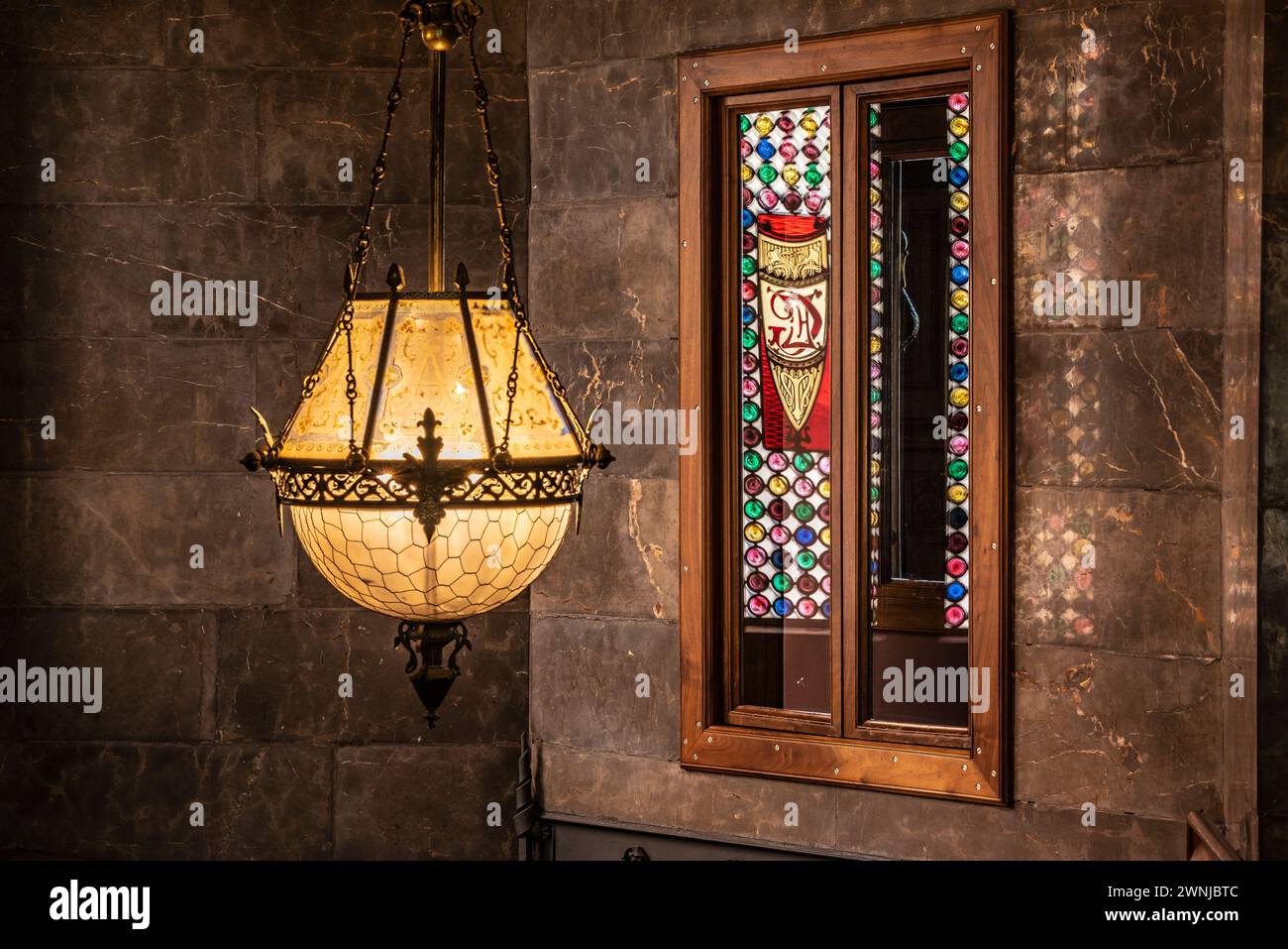 Lamp and window with a stained glass window inside the Palau Güell ...