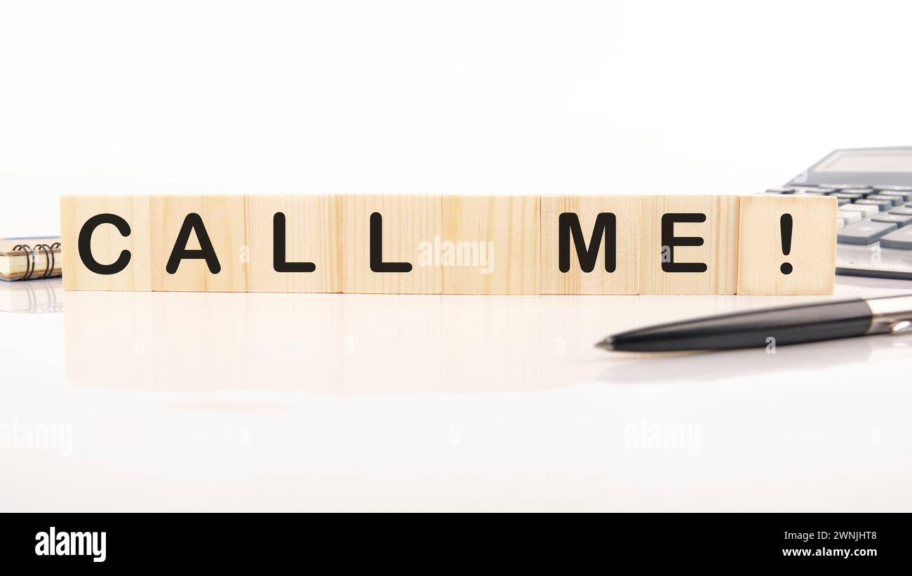 Text Call me written on wooden cubes next to a calculator, pen, notepad ...