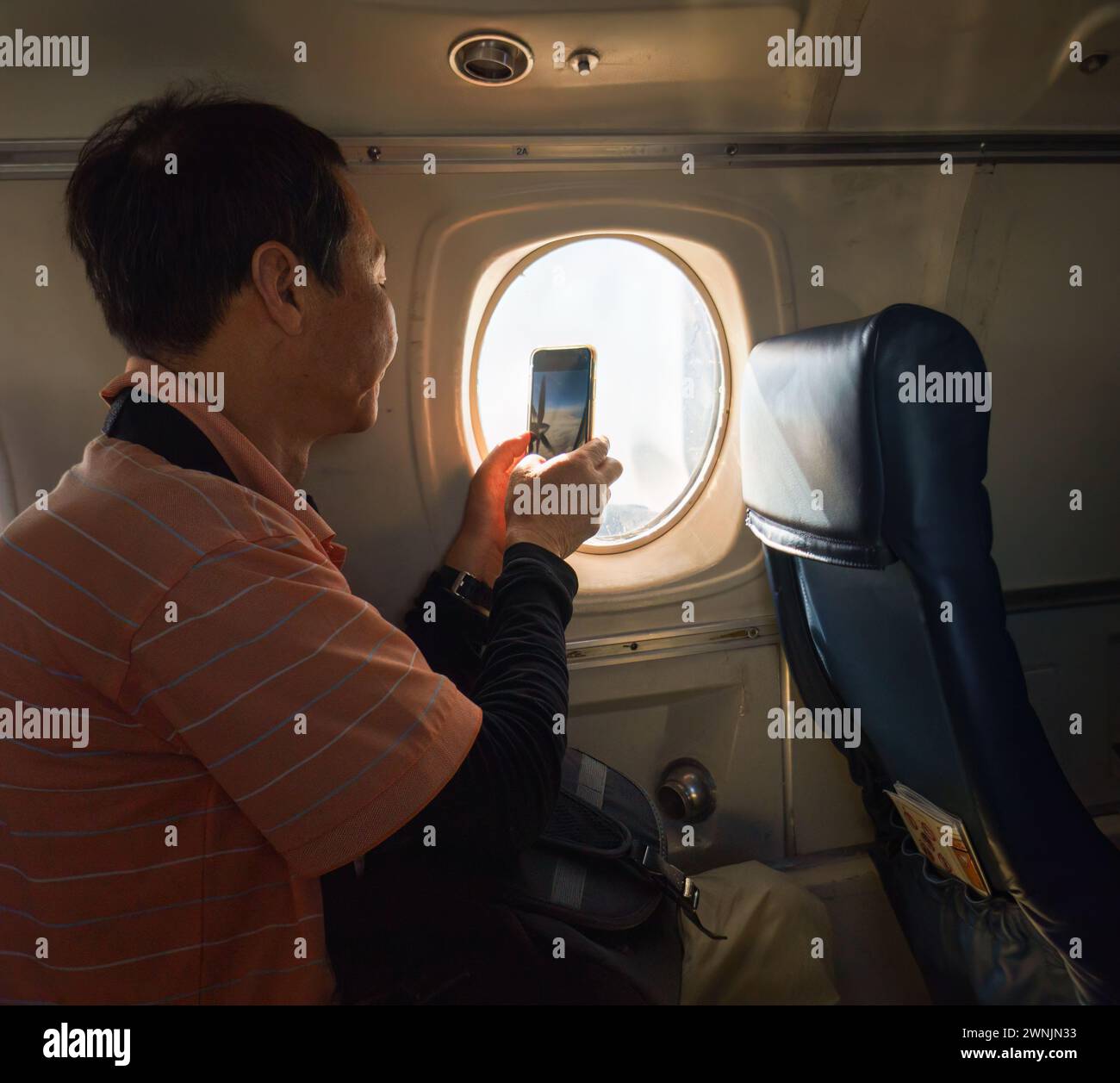 Passenger taking photos using his smartphone through the aircraft ...