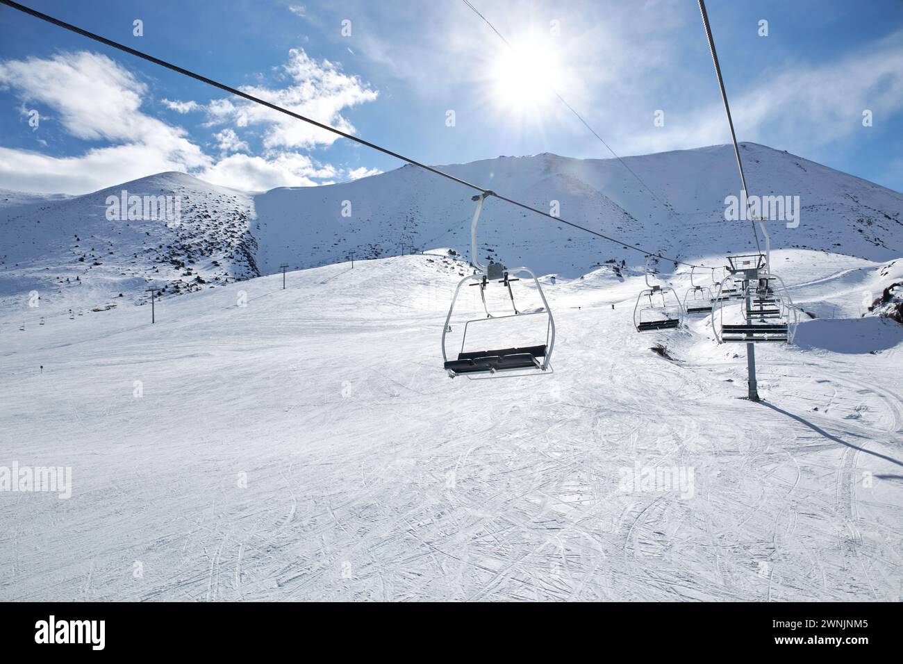 Ski lift pole with empty chairs at winter resort. Sunny day, blue sky ...