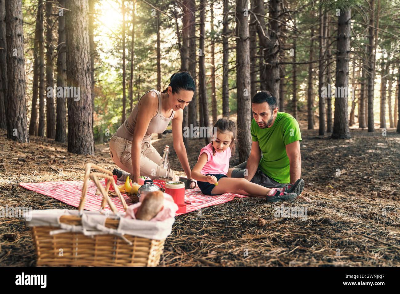 Family having a joyful picnic among trees, sharing food and smiles in a ...