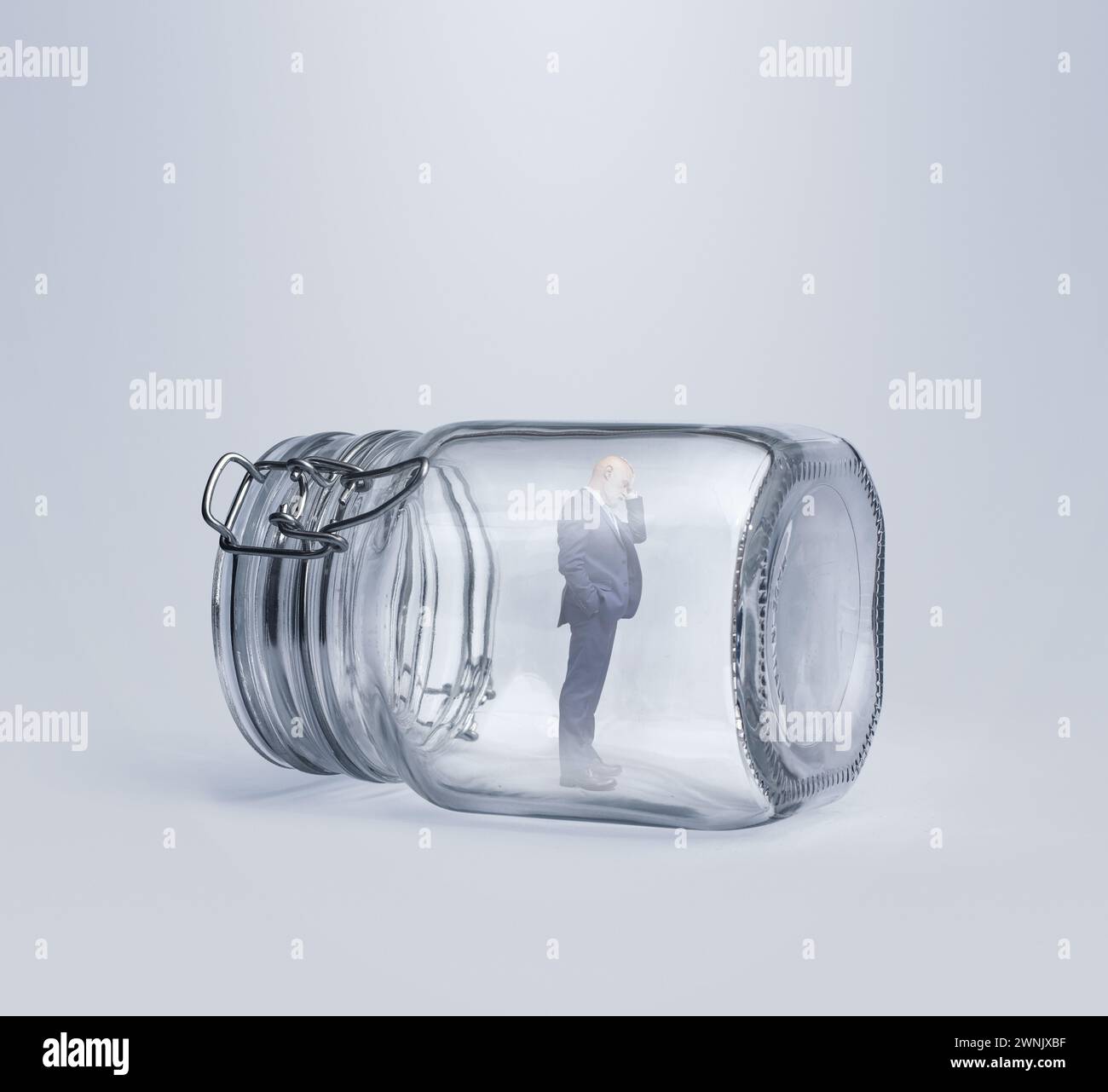 Depressed senior businessman trapped inside a glass jar, he is standing ...