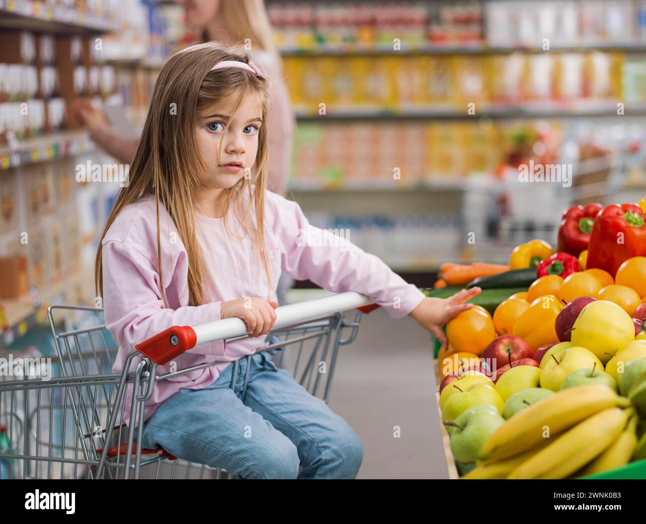 Cute surprised girl taking a fruit in the produce section at the ...