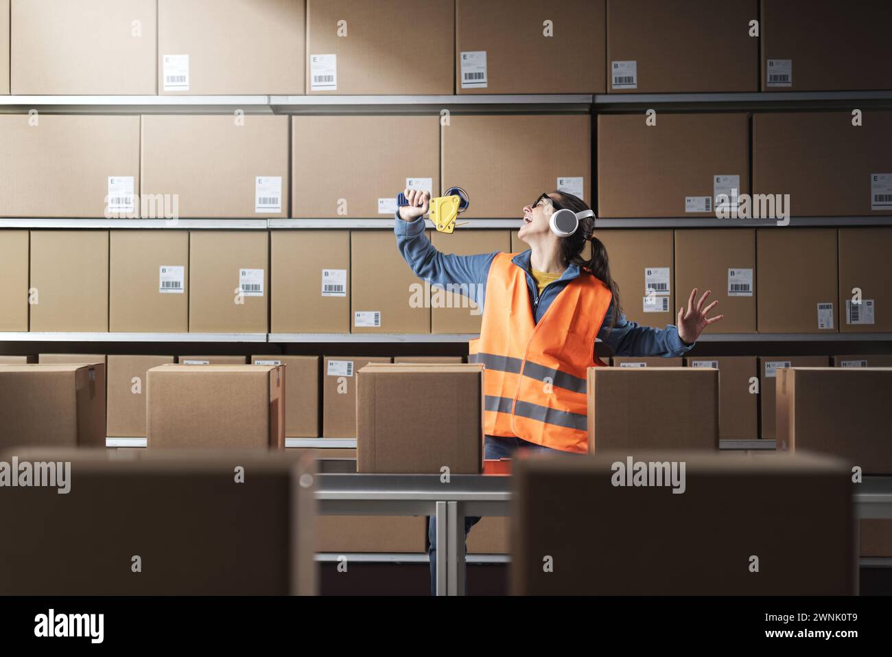 Cheerful distracted warehouse employee singing and dancing instead of ...