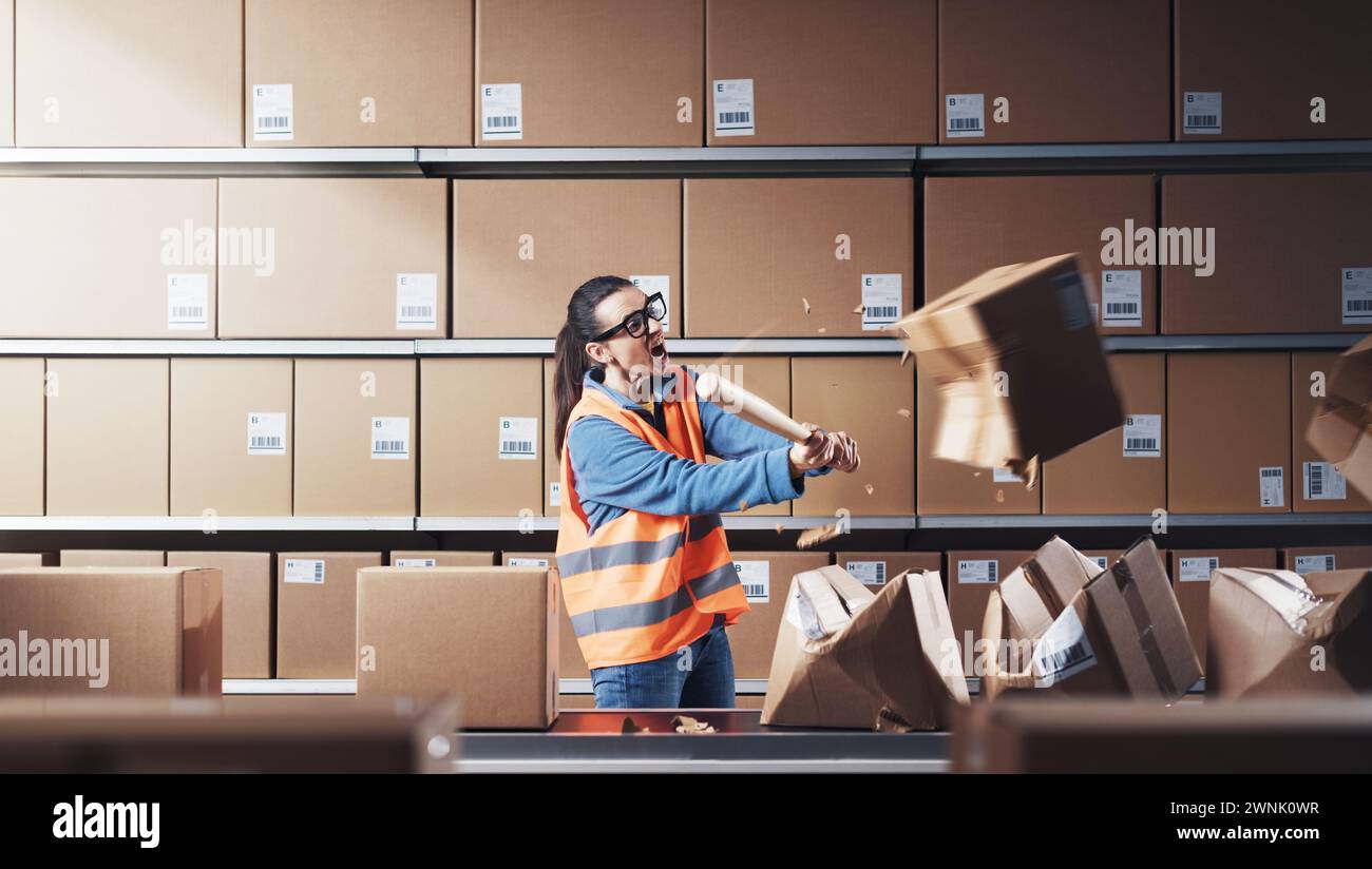 Aggressive rebellious warehouse worker smashing boxes at work, she is ...