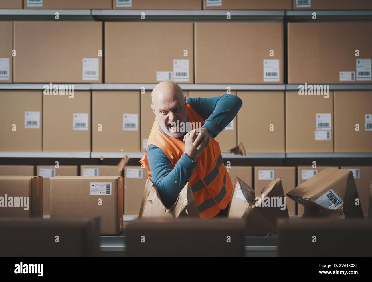 Furious rebellious worker tearing boxes at the warehouse and screaming ...