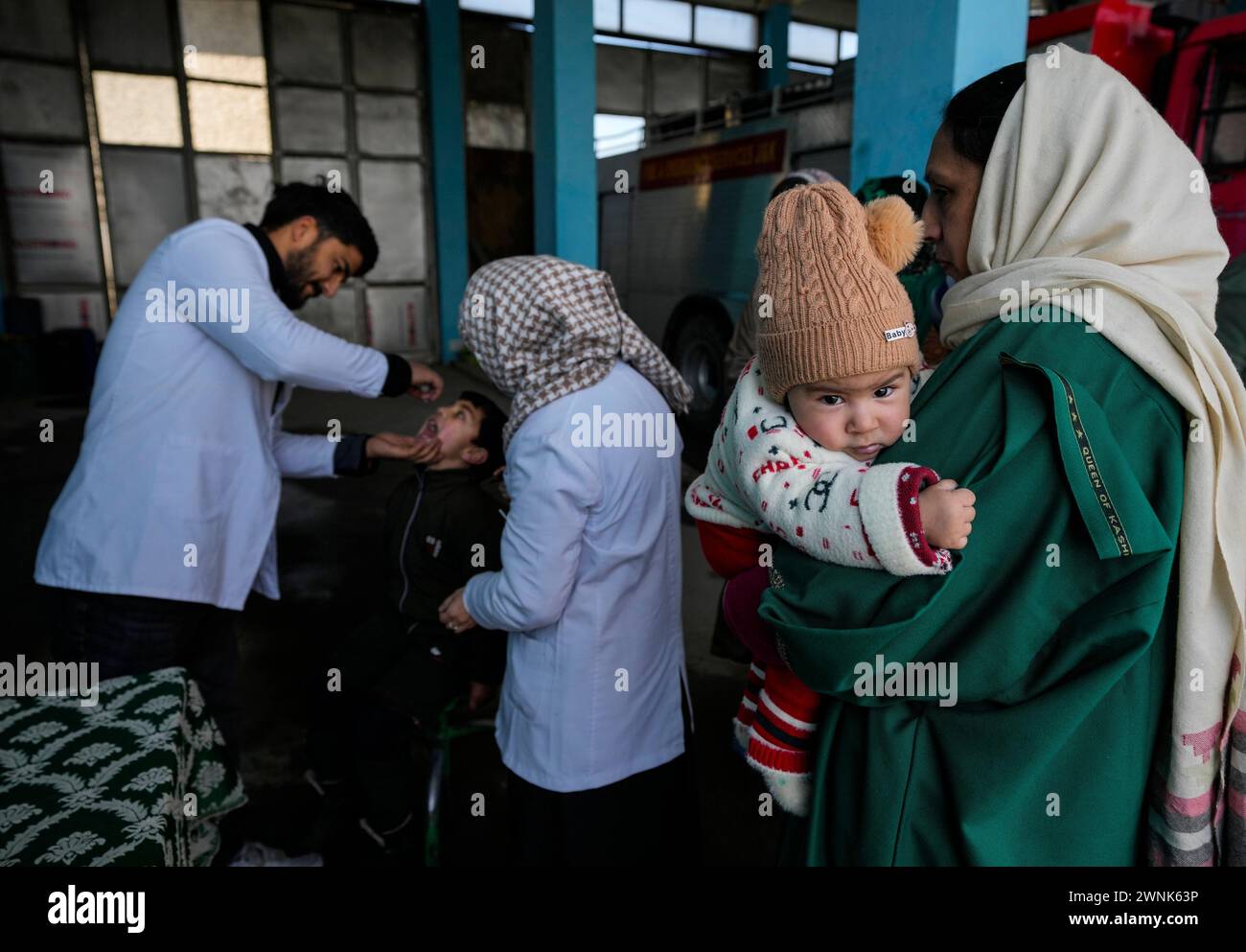 A government health worker administers polio drops to a child in ...